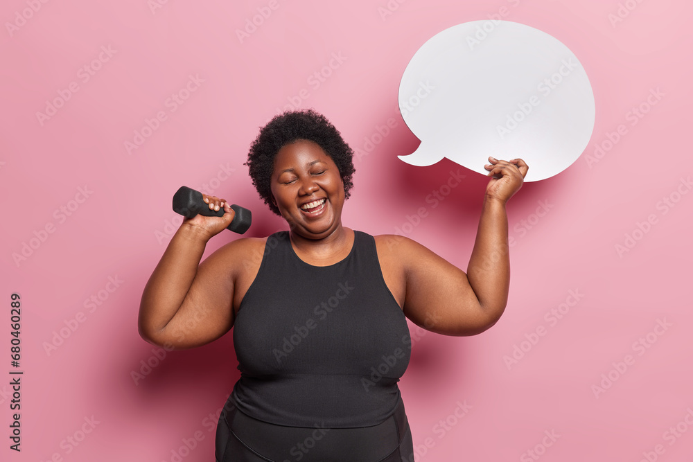 Obese dark skinned African woman dressed in black tracksuit lifts ...