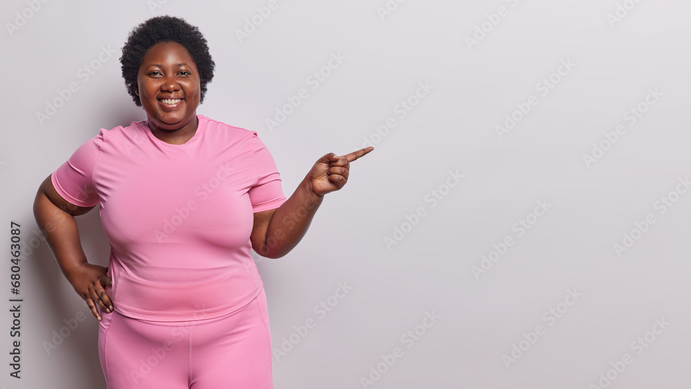 Plus size dark skinned woman dressed in pink sportswear points index ...