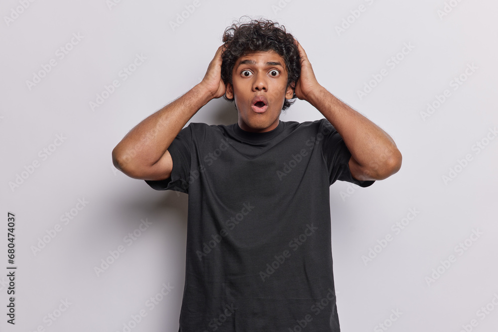 Waist up shot of scared frightened Hindu man with curly hair keeps ...