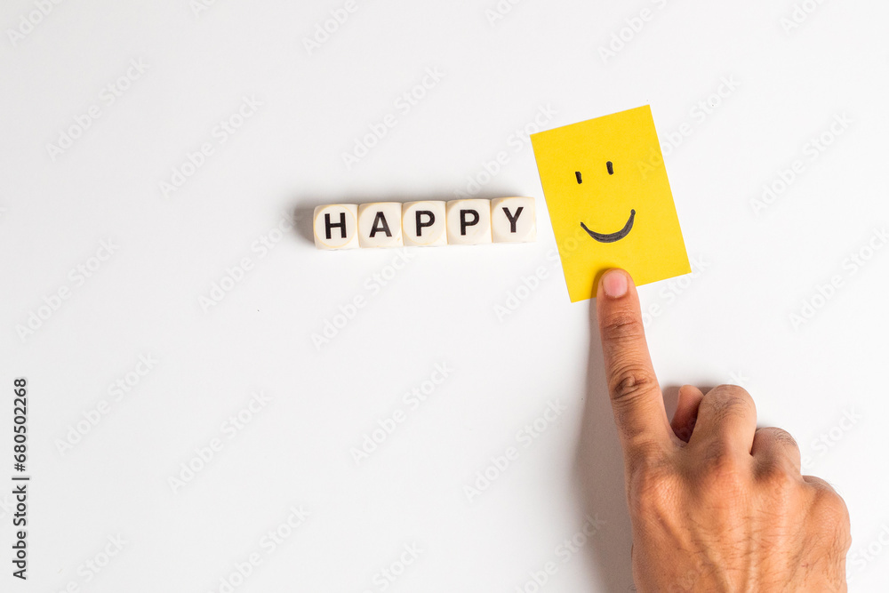 dice form word Happy, smiley face on yellow sticky note, finger on the ...