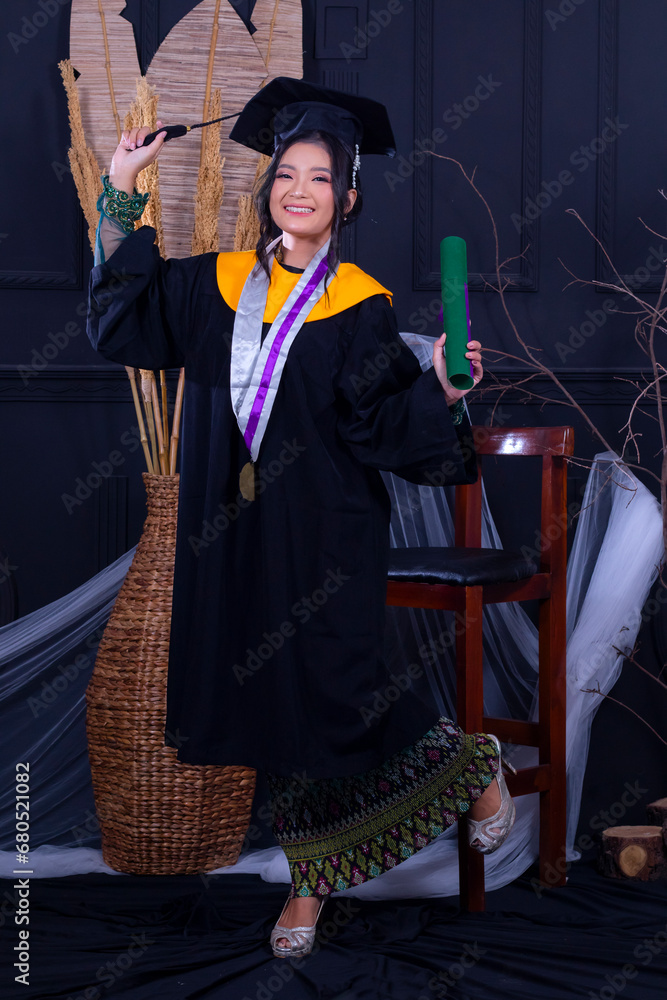 Beautiful exotic Asian woman graduating, smiling cheerfully, hands ...