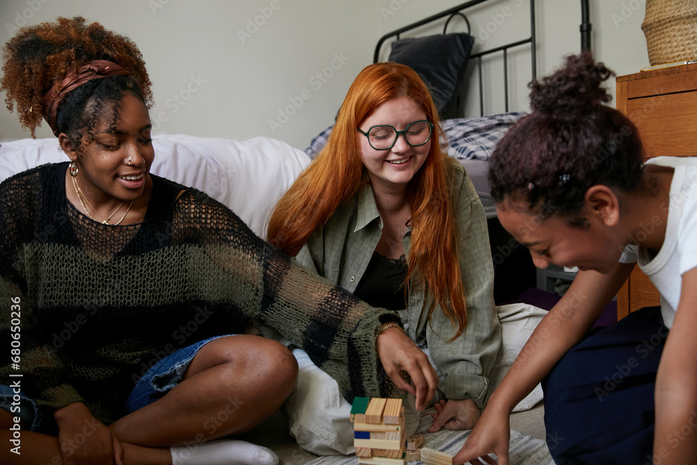 Group of diverse friends playing a game of jenga on the floor in ...