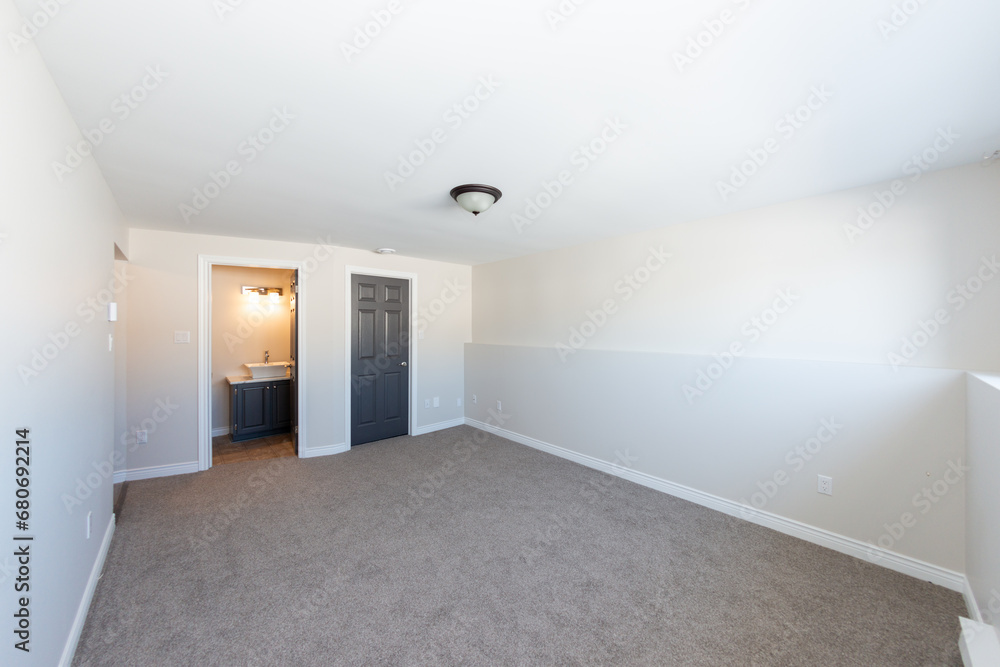 An empty master bedroom with a white ceiling, beige painted walls and grey carpet in a house ...