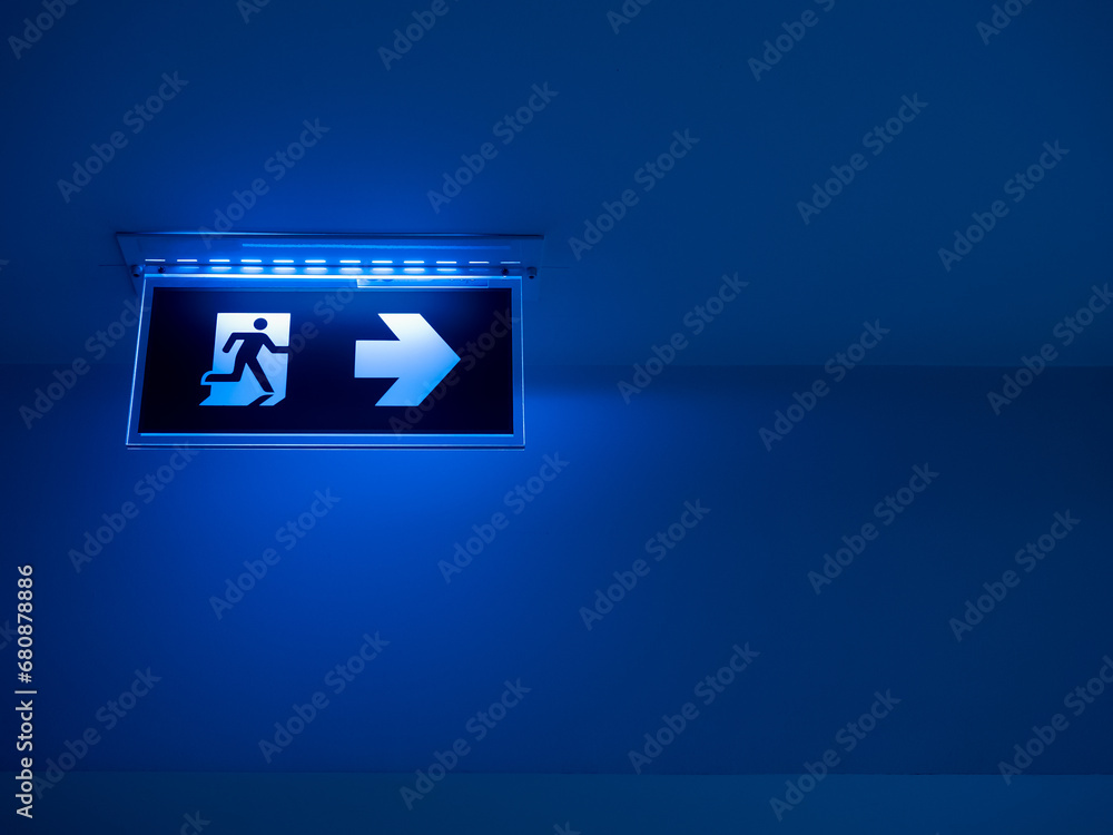 Blue tone of LED light fire escape sign hang on the ceiling in the dark ...