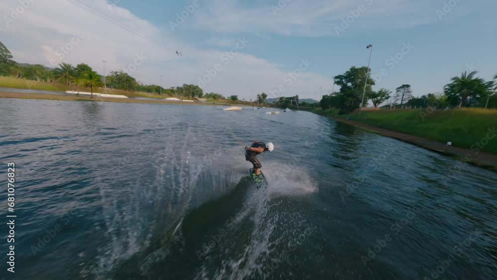 Skilled wakeboarder man riding board jumping difficult trick slim ...
