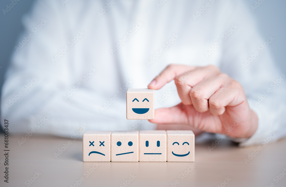 Hand chooses smiley happy face on wooden cube from normal and sad ...