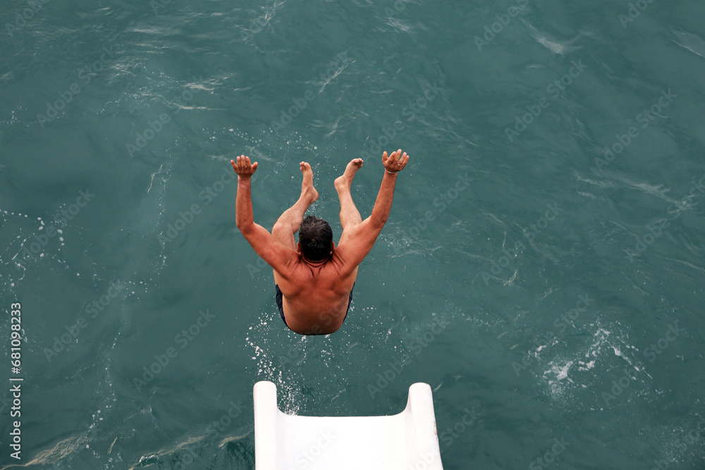 Man jumping in sea from water slide, top view. Beach vacation and ...