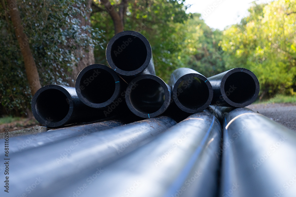 Few new plastic water pipes are stacked on the street, ready to be ...