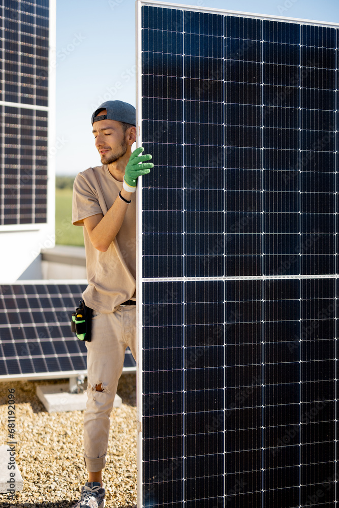 Portrait of a man standing with solar panel on a rooftop of his house ...