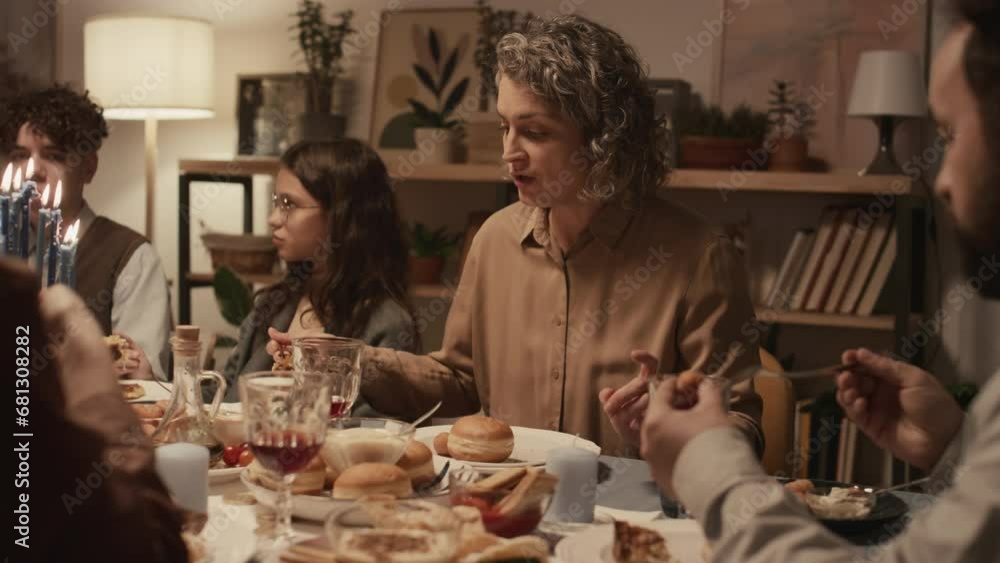 Medium shot of large Jewish family sitting around table during Hanukkah ...