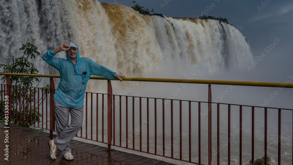 A man is standing on the observation deck at the powerful waterfall ...