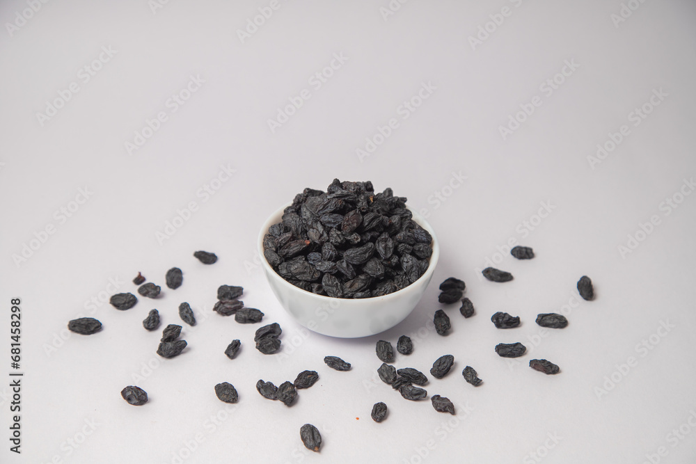 Dried black raisin on white bowl with white background, Dried black raisin scattered on the ...
