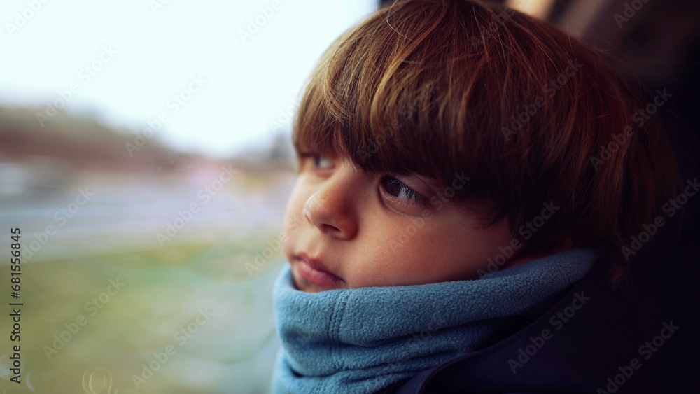 Introspective young boy with scarf, nestled by the train window, lost ...