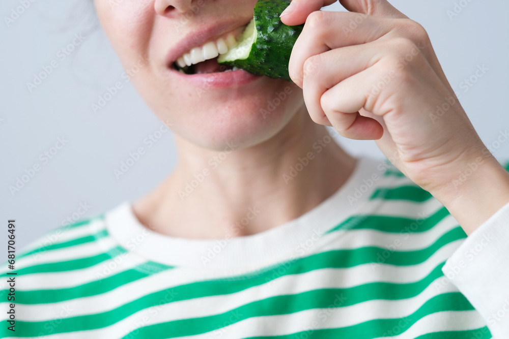 Focus on cucumber close-up, woman holding a fresh bitten cucumber in ...