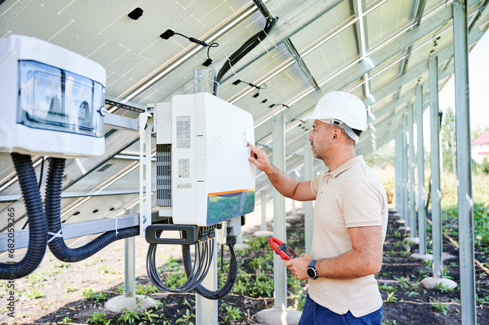 Professional worker checking voltage on solar inverter. Male using ...