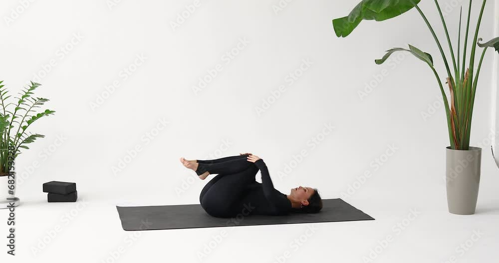 Woman practicing yoga performs Pavana Muktasana exercise, wind release ...