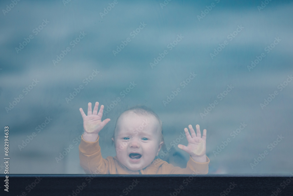 Child crying inside house and looking through window for mom. The upset ...