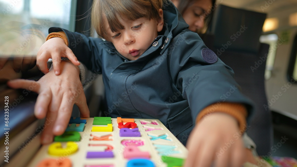 Young boy settled on mother's lap during train journey, engaging in ...