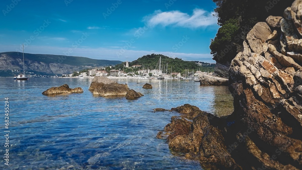 Calm sea water, cliffs with growing trees and moored yachts and boats ...
