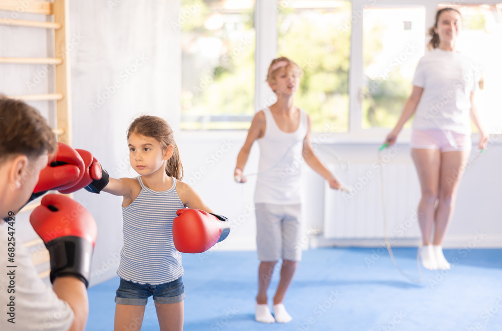 Girl and dad are boxing in gym, father helps daughter child to work out ...