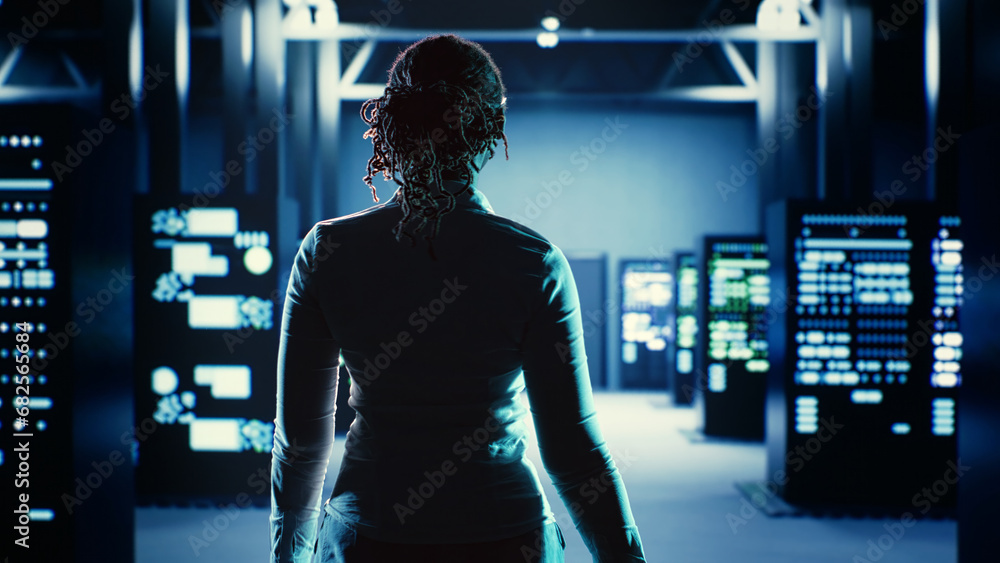 Skillful employee strolling around data center server rows, looking for damages in high tech ...