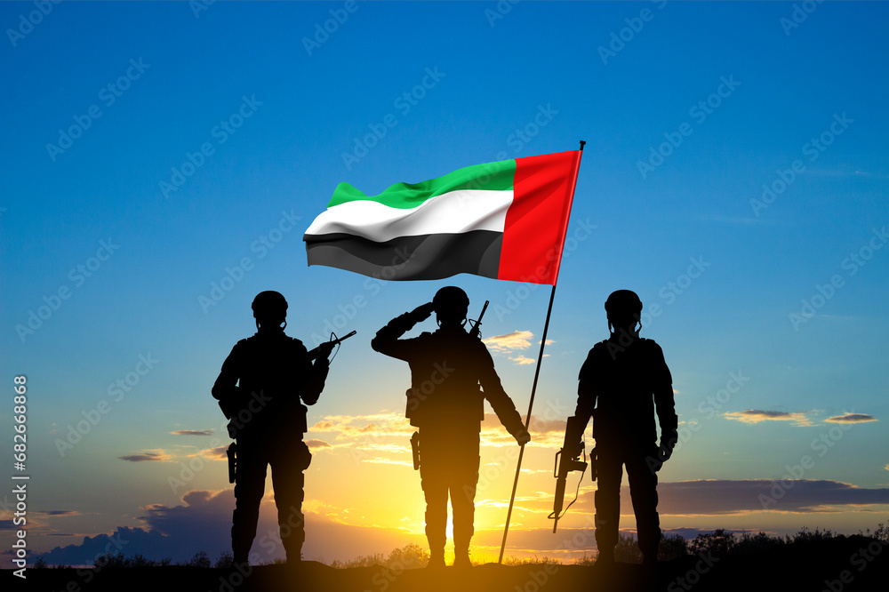 Silhouettes of soldiers with the flag of UAE against the sunset. Armed ...