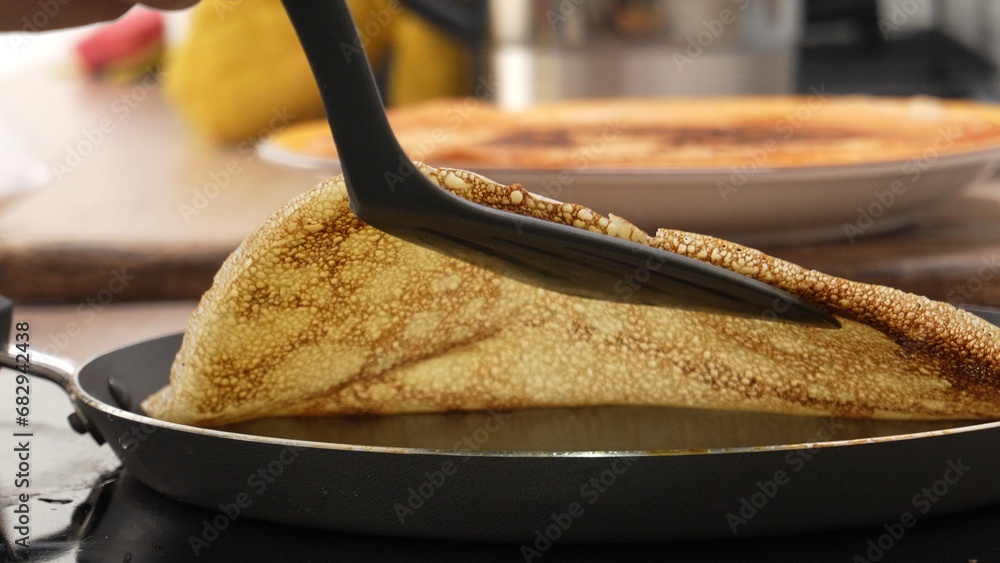Spatula lifting a pancake, revealing underside texture. The action ...