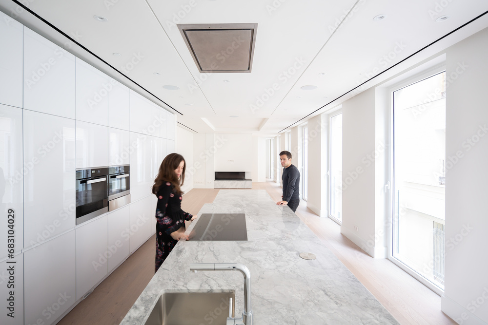 Woman and man standing opposite each other at a kitchen island in a ...