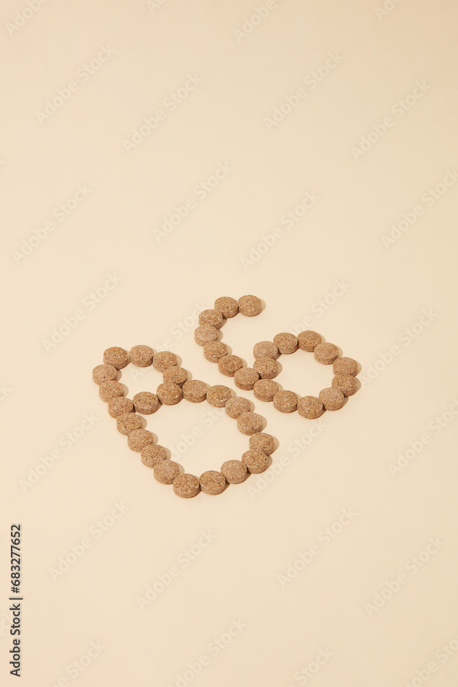 Round brown pills are arranged in a B6 shape on a pastel background ...
