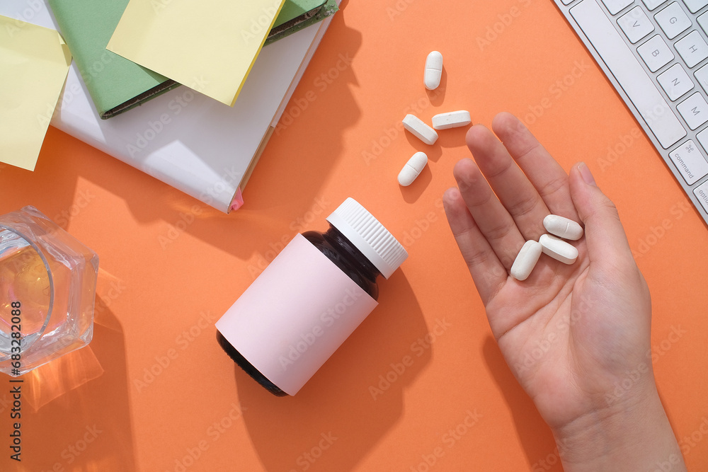 White pills in a woman's palm, an unlabeled pill bottle, a glass of ...