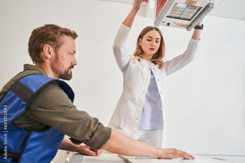 Woman doctor making arm examination to man patient using x-ray machine ...