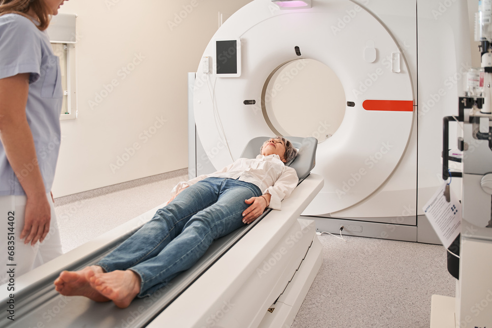 Mature female patient laying on bed and waiting X-ray procedure at ...