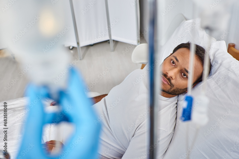 focus on ill indian man lying in hospital bed in ward and looking at ...