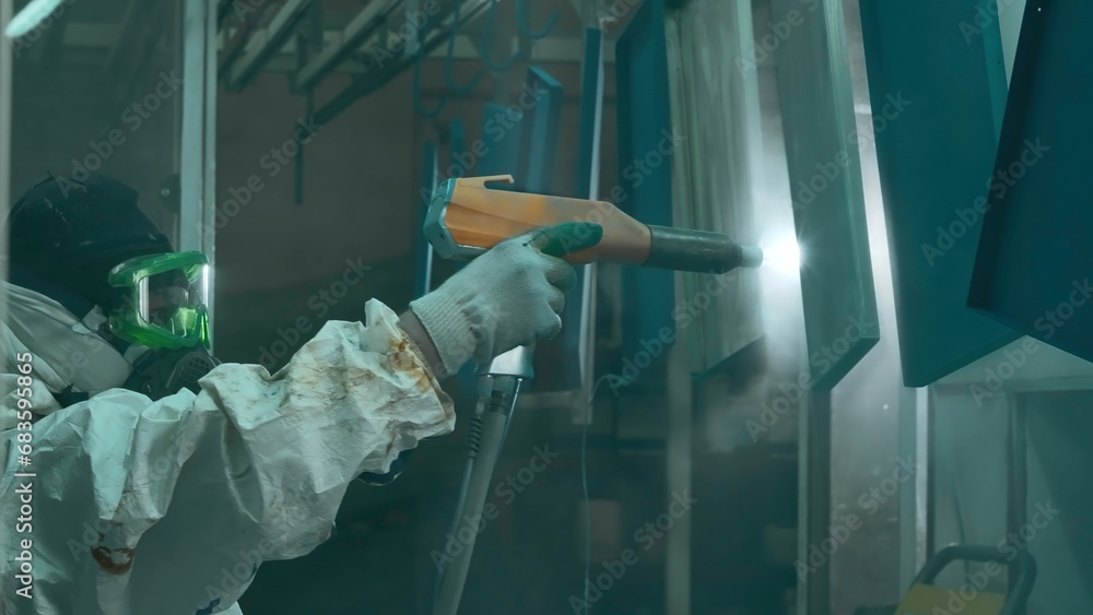 Worker spray paints metal sheets. Creative. Worker in uniform paints ...