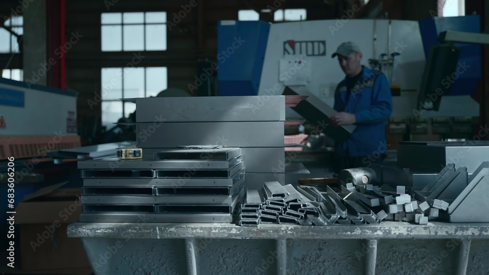 Metal parts on factory table with working assembler. Creative. Worker ...