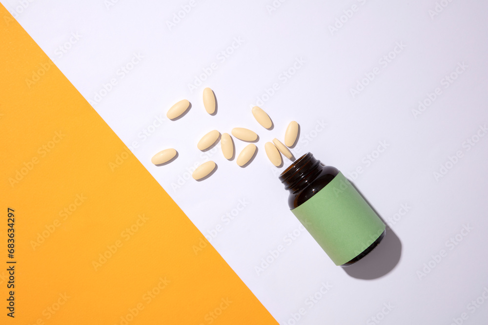Pastel colored tablets poured from an unbranded medicine bottle on a ...