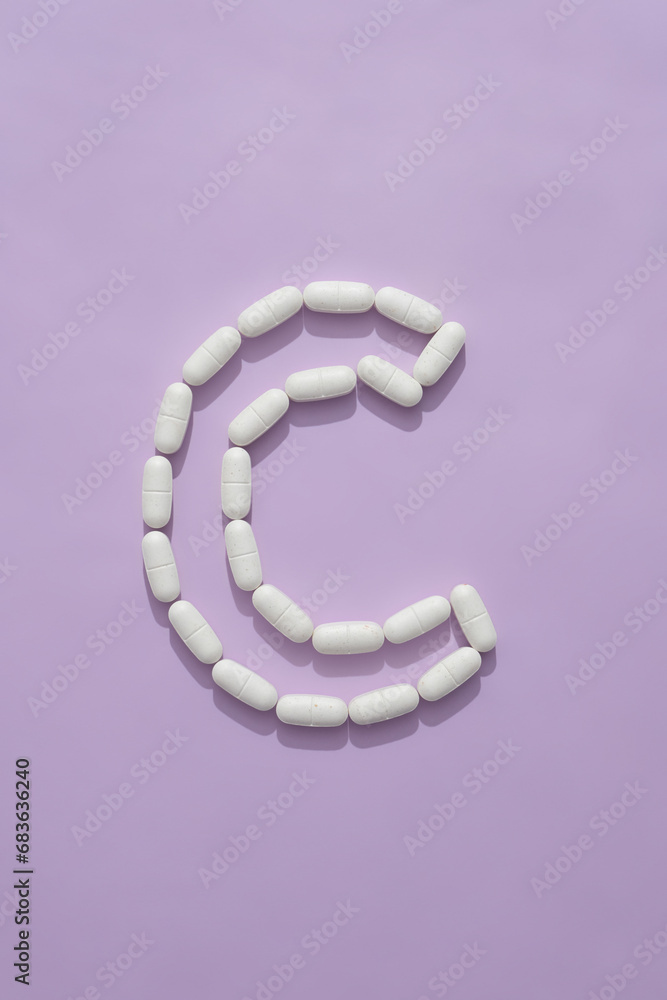 White tablets are arranged in a C shape on a purple background. Vitamin ...