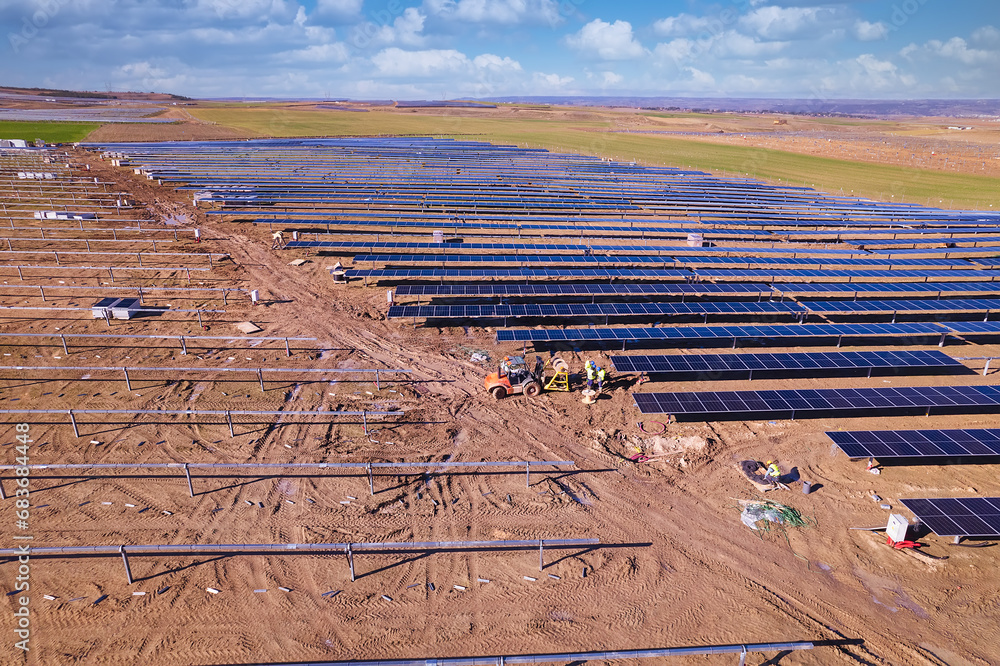 Elevated view of three workers installing solar panels in a new solar ...