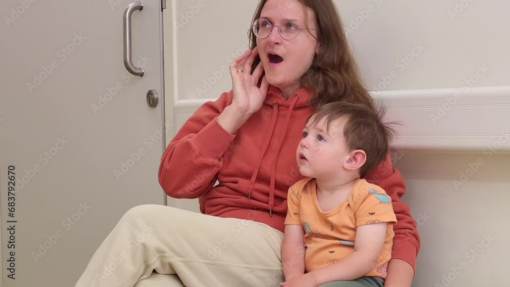 A woman and her child are waiting for their appointment in the clinic ...