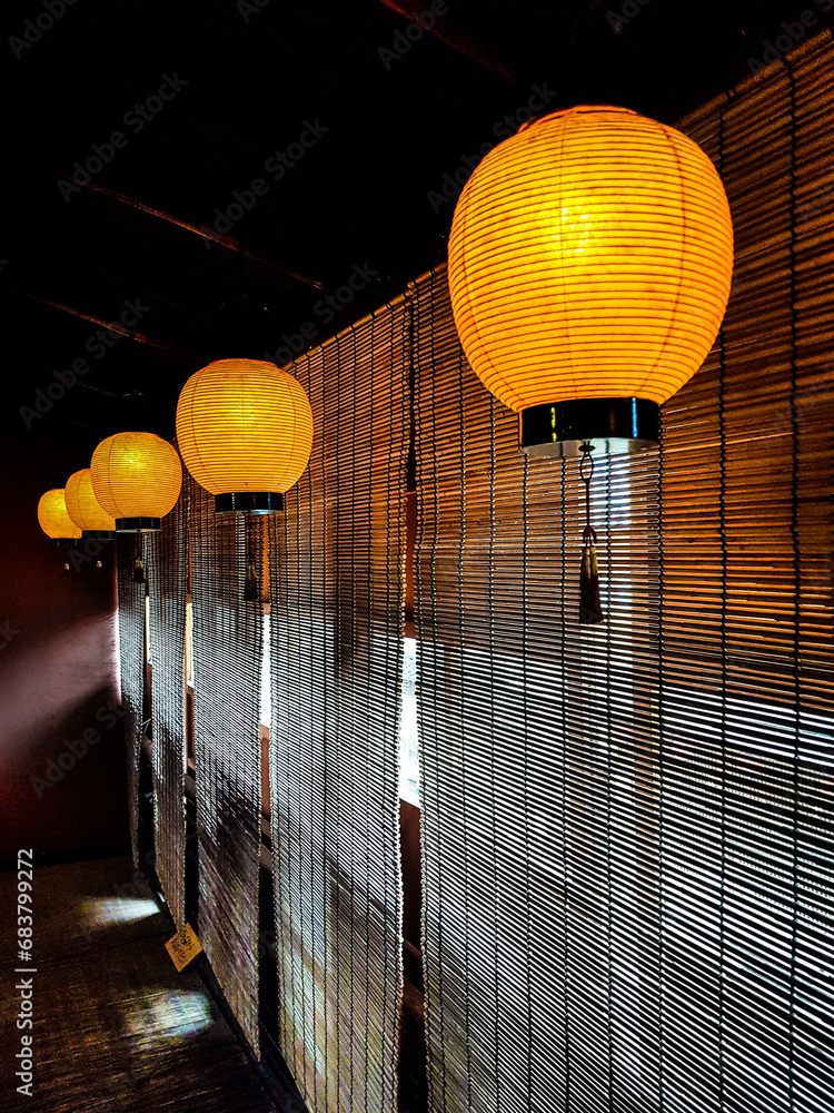 A row of yellow Japanese lanterns hanging in the hallway of a ...