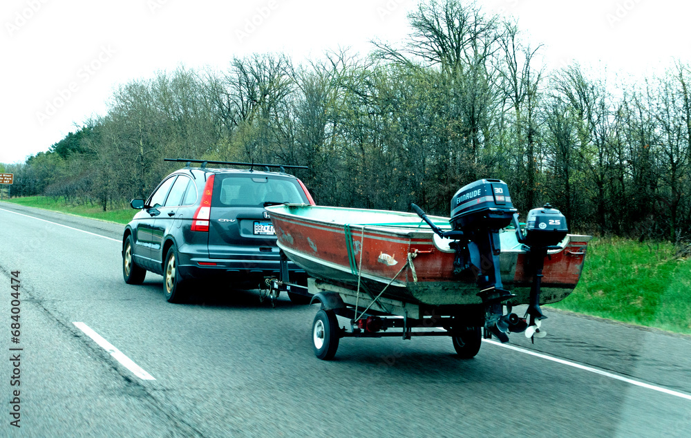 Car hauling Lund aluminum boat with a larger Evinrude outboard motor ...