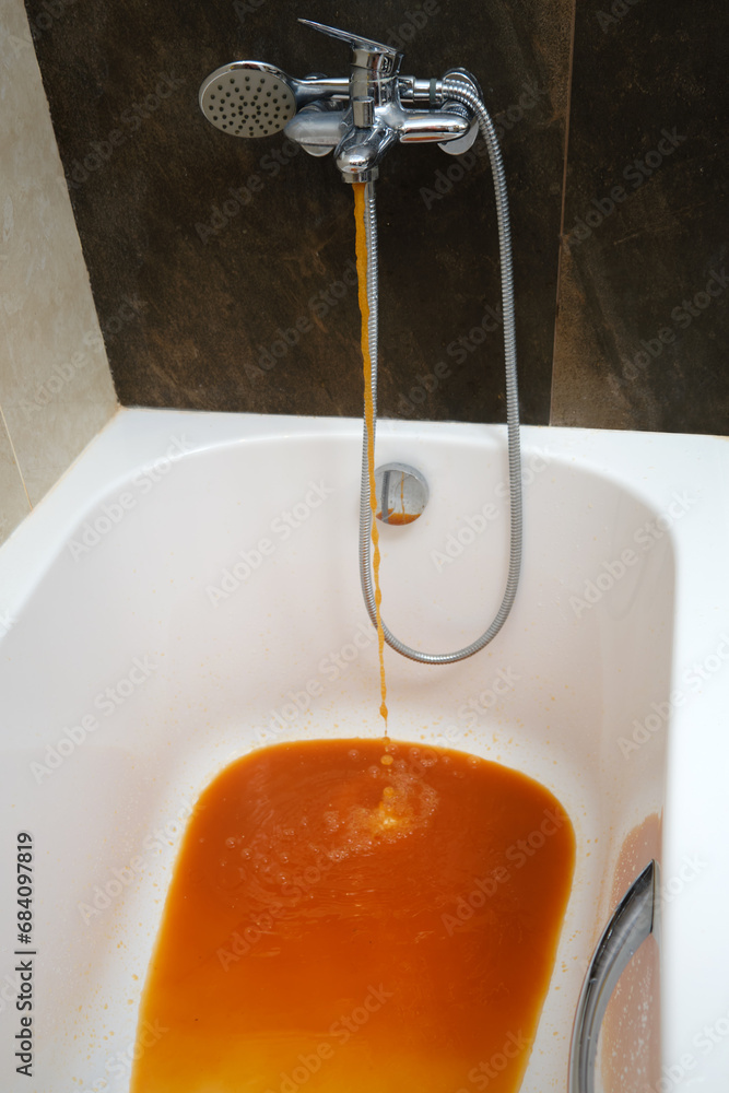 Rusty water flows from the faucet into the bathtub on the home bathroom ...