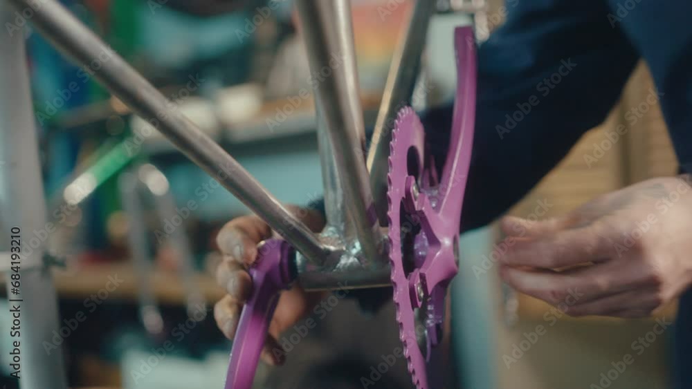 Close-up view of hands of male mechanic attaching crankset to bottom ...