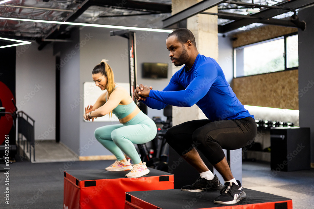 A couple of young people of different ethnicities are jumping on a ...