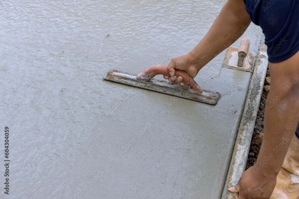 Builder mason worker leveling fresh concrete pavement wet cement using ...