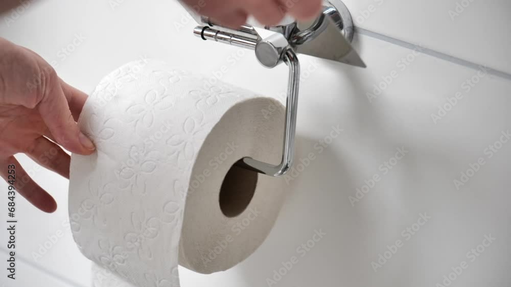 Toilet paper. Hands putting a new roll of toilet paper into the holder ...
