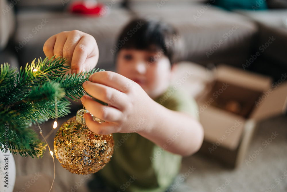 Kid boy decorating Christmas tree put off balls from the box authentic ...
