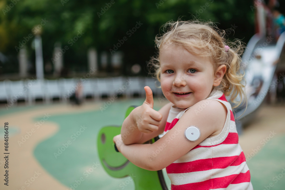 Little girl with diabetes giving thumbs up playing on seesaw on ...
