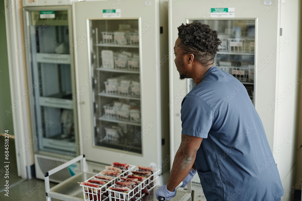 Lab technician pushing trolley of blood bags Stock Photo | Adobe Stock