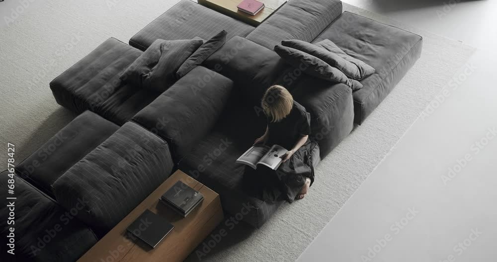Overhead view of woman sitting on comfort modular sofa and reading ...